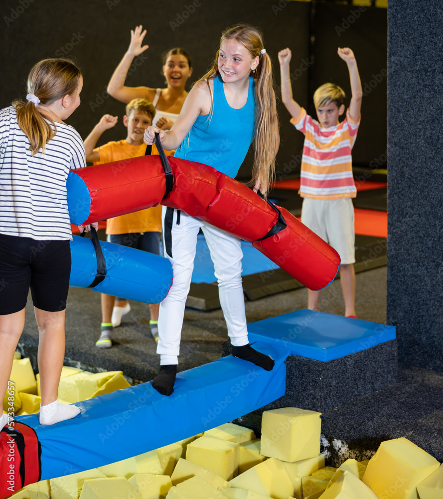 Smiling children having funny wrestling by inflatable logs in indoor ...