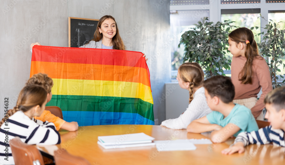 Young female teacher showing flag of LGBT to schoolchildren preteens ...