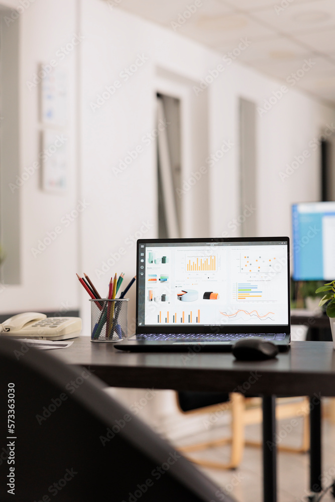 Portable computer executing cost analysis software on the office desk ...