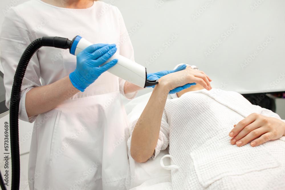 doctor cosmetologist makes laser cleaning of the skin on the arm of the ...