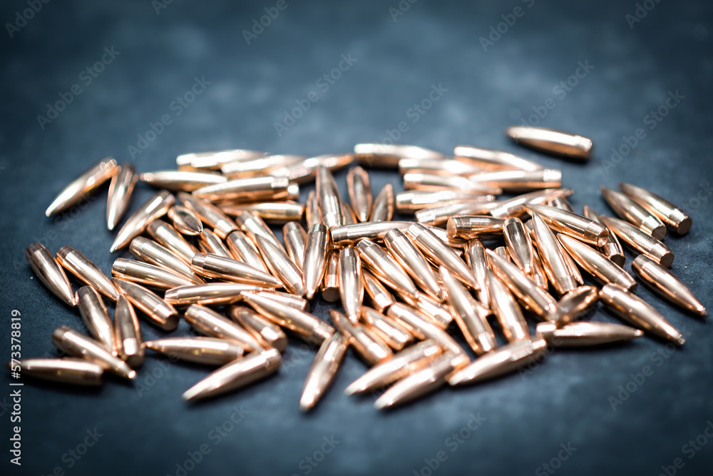 Rifle bullets are scattered on a table for loading into a rifle gun for ...