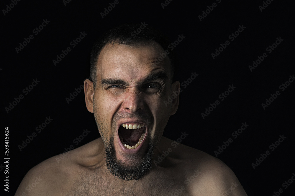 Close-up of a young, angry, disgruntled man looking into the camera and ...