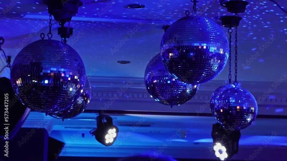 Mirror disco balls hang from ceiling and spin in nightclub during dance ...