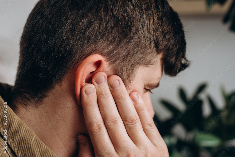 Foto de Closeup up of upset young male having ear pain touching painful ...