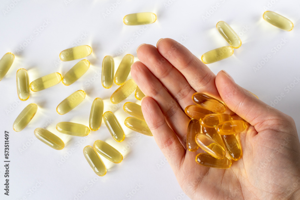 Fish oil in a woman's hand on a white background with scattered ...