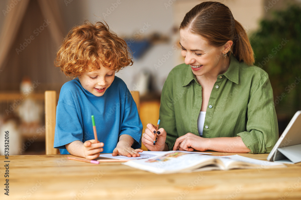 Cheerful mother doing homework with son at home Stock Photo | Adobe Stock