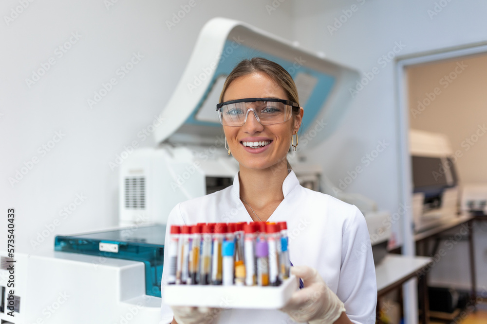 Blood test tubes. Female scientist examining blood test tubes at her ...