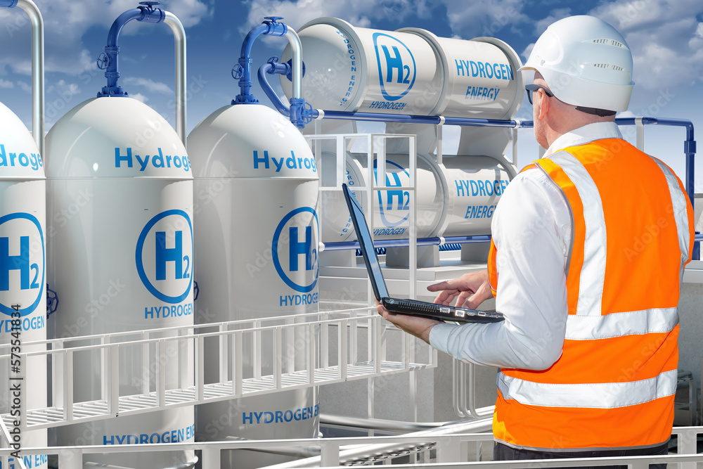 Man technologist with laptop. Hydrogen energy. Tanks with H2 symbol for ...