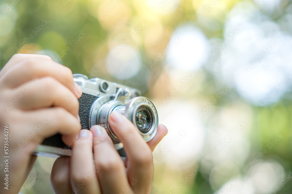 film camera in the hands of a girl taking a picture. Green trees ...