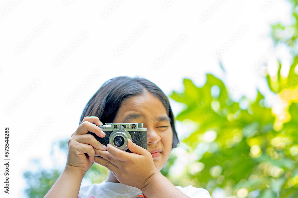 film camera in the hands of a girl taking a picture. Green trees ...