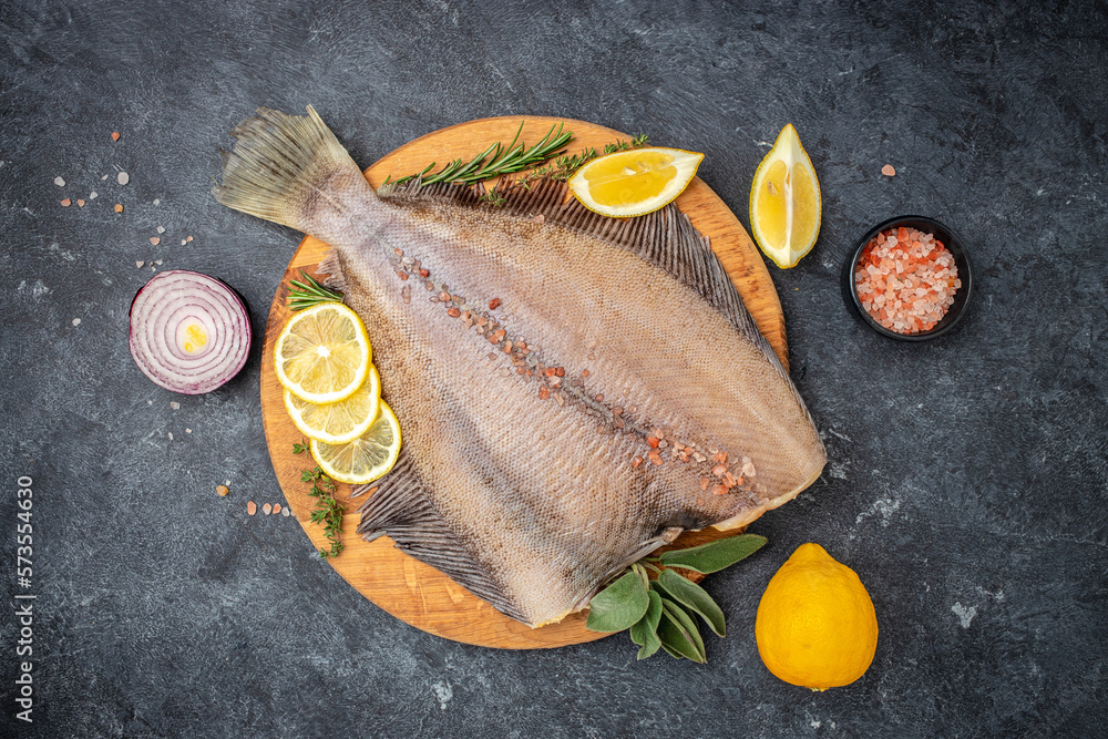 Raw flounder fish flatfish with lemon and spices on a dark background ...