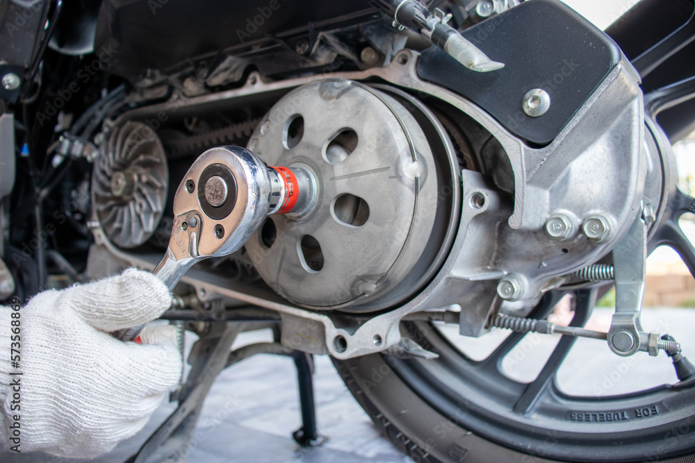 A mechanic is inspecting and repairing a motorcycle in a garage. and ...