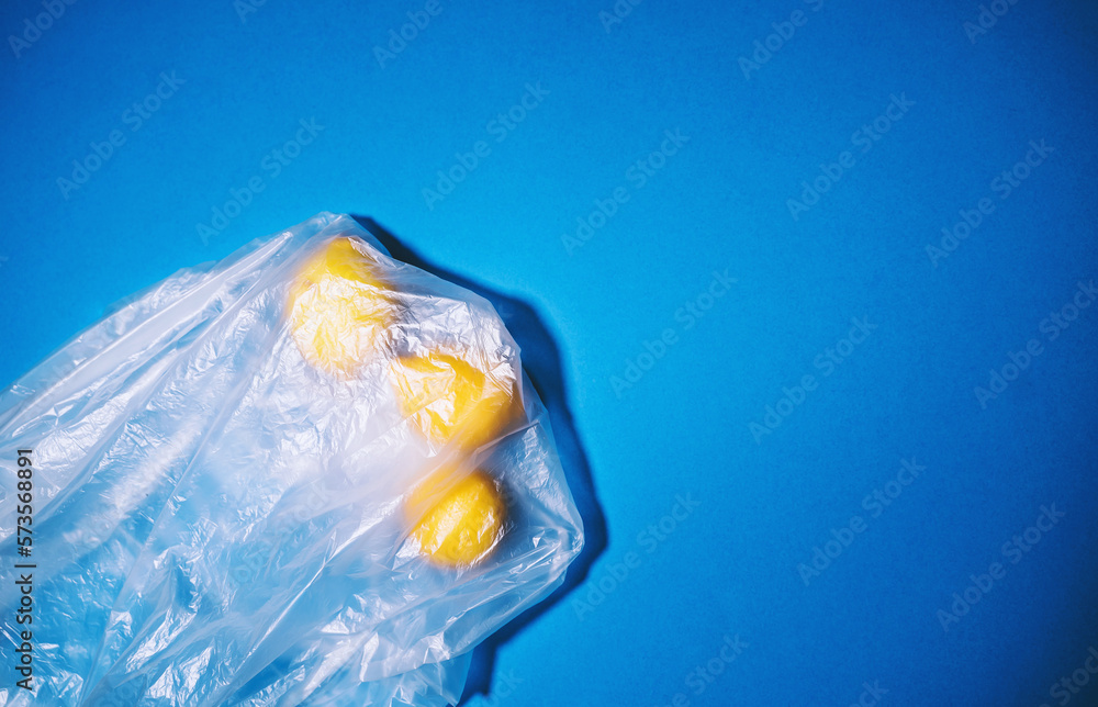 Lemon fruits in transparent plastic bag on blue background. Concept ...