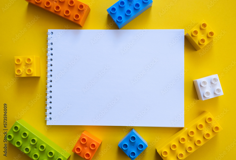Spiral notepad on yellow background surrounded by plastic building ...