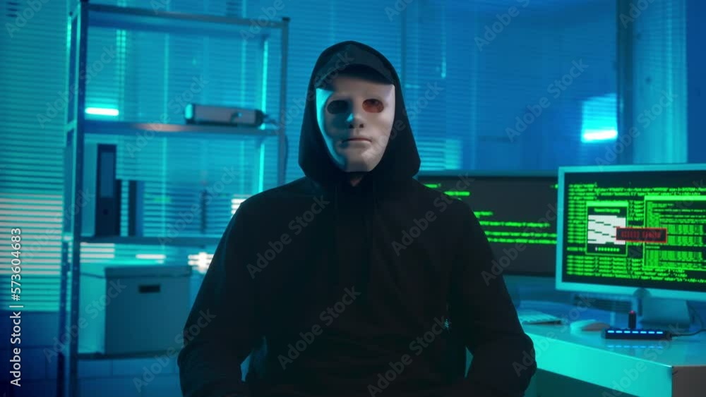 Portrait of a hacker in a white mask looking confidently at the camera ...