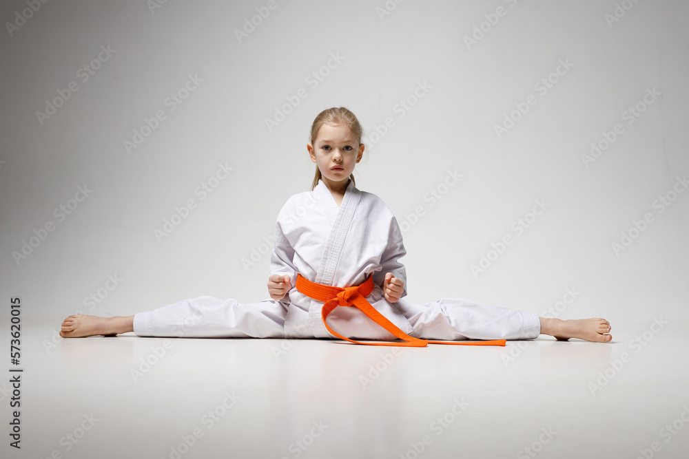 Little girl in a split pose on a white background, child karate fighter ...
