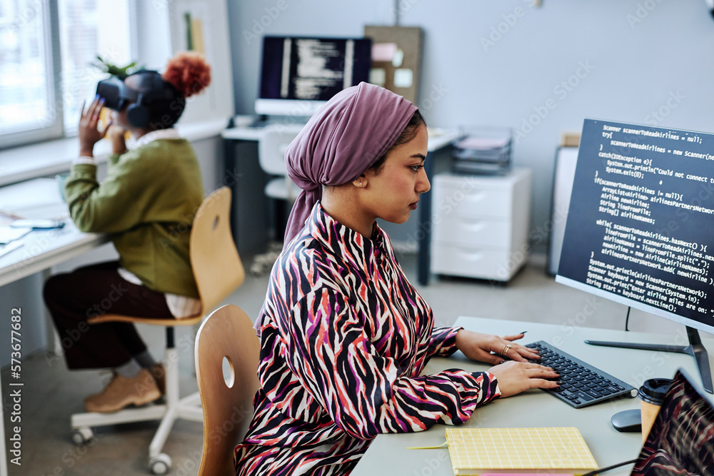 Side view portrait of Muslim young woman as software developer writing ...