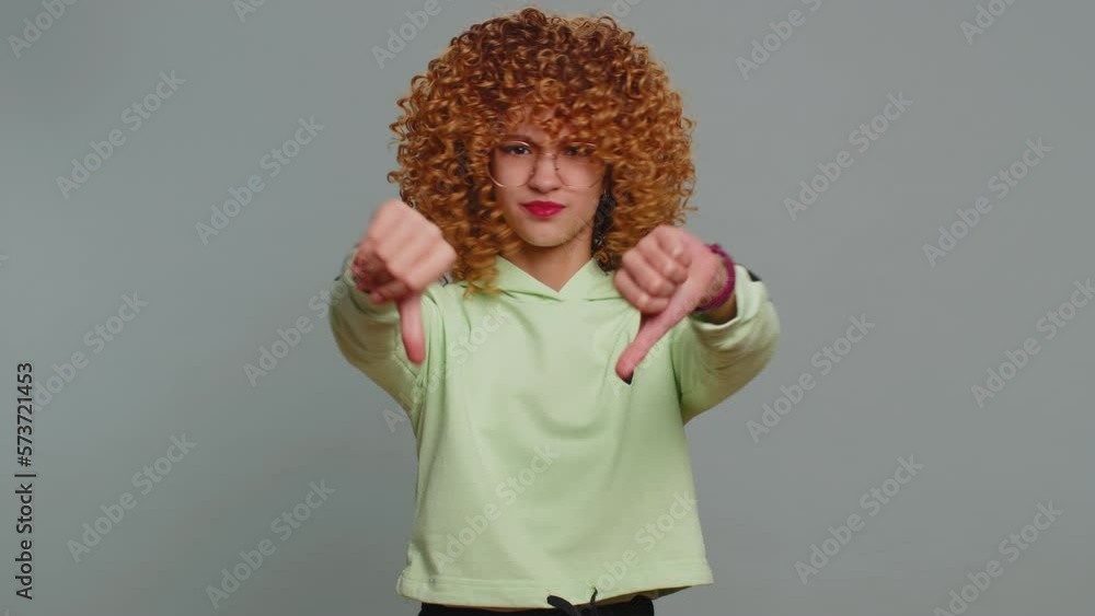 Dislike. Upset young child girl kid with curly hair showing thumbs down ...