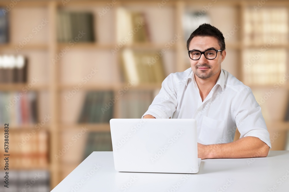 Clever student with computer working in library Stock Photo | Adobe Stock