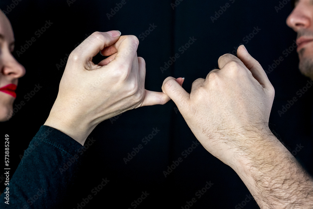 man and woman holding hands on a black background, friendship sign ...