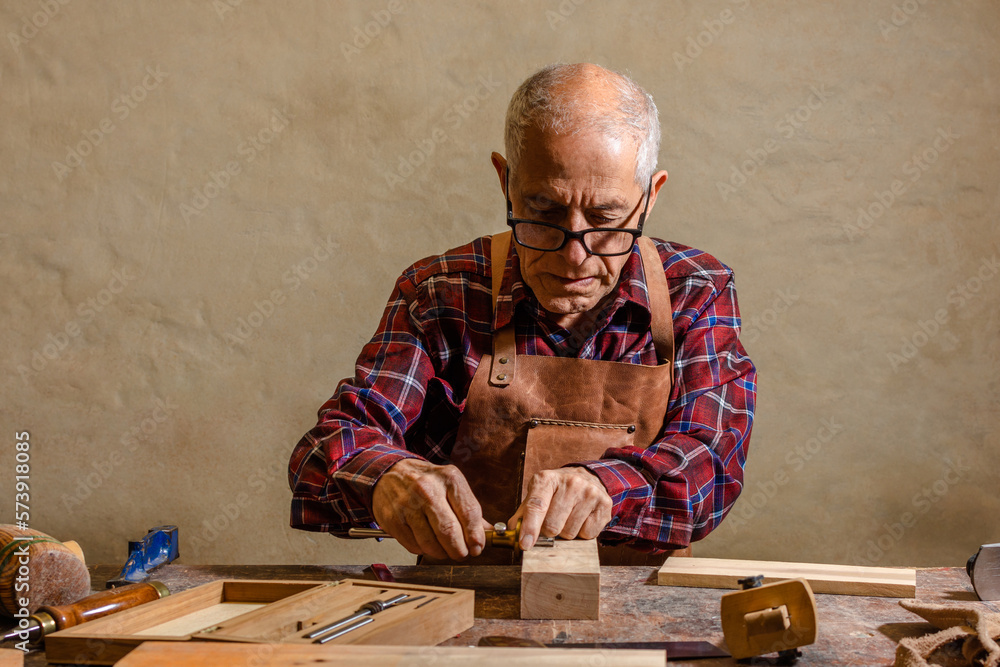 Old carpenter working in his workshop, using hand tools to shape a ...