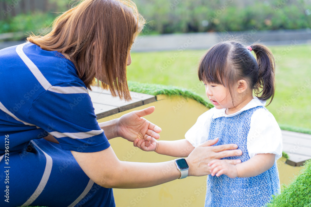 little girl receive love and hug from her mom after falling on ground ...