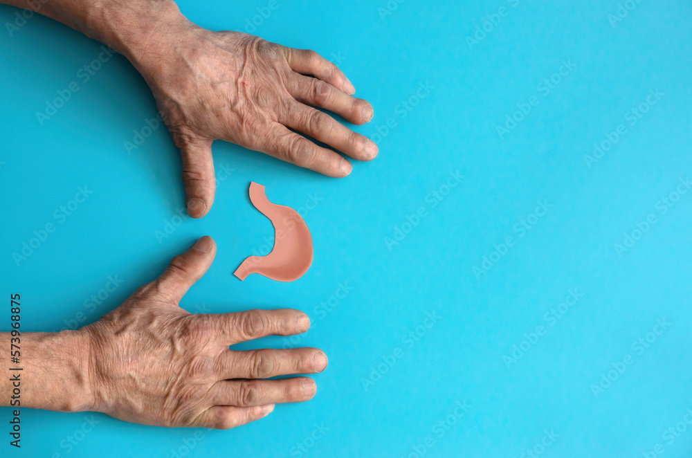hands of an old man and a symbol of the stomach on a blue background ...