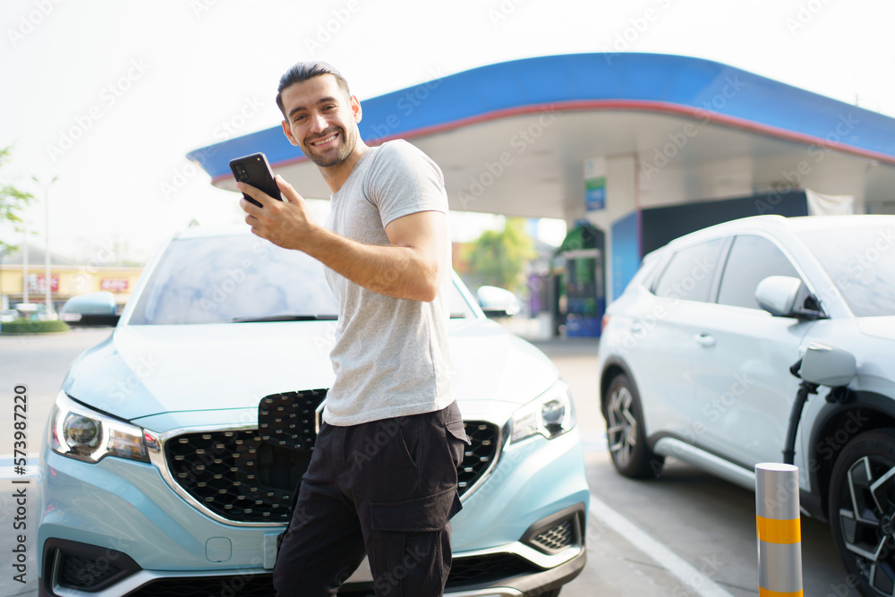 Handsome Asian young man holding an EV plug connector and attaching ...