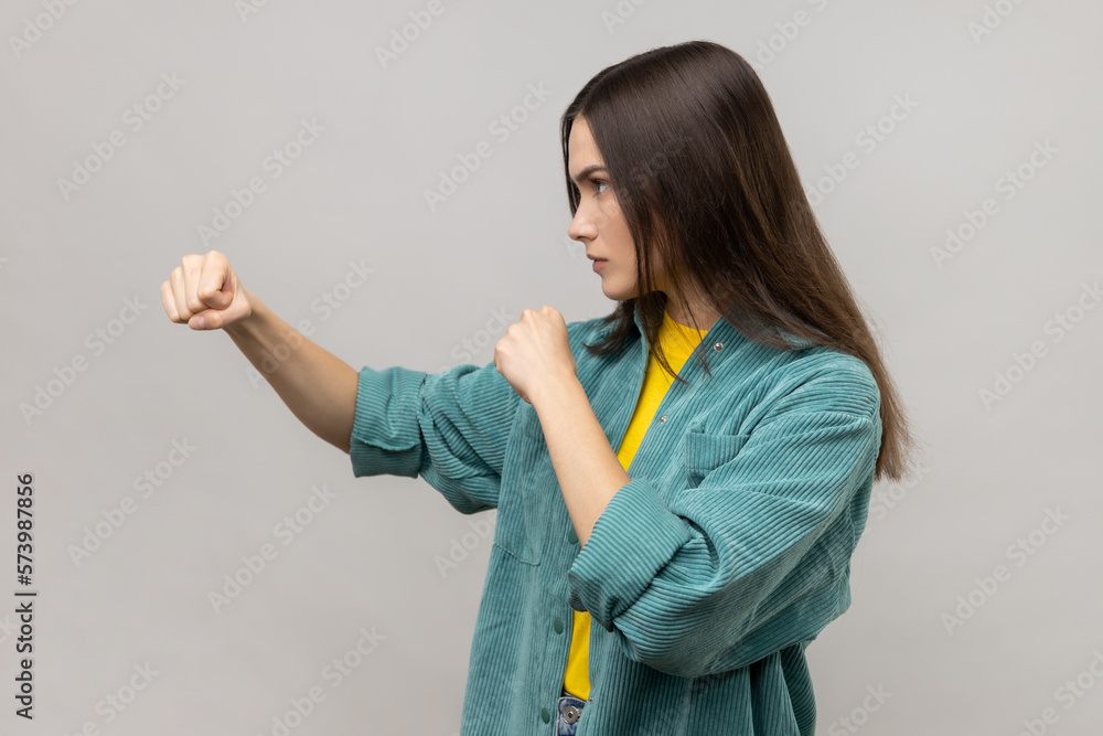 Side view of woman standing with clenched fists, furious look, ready to ...