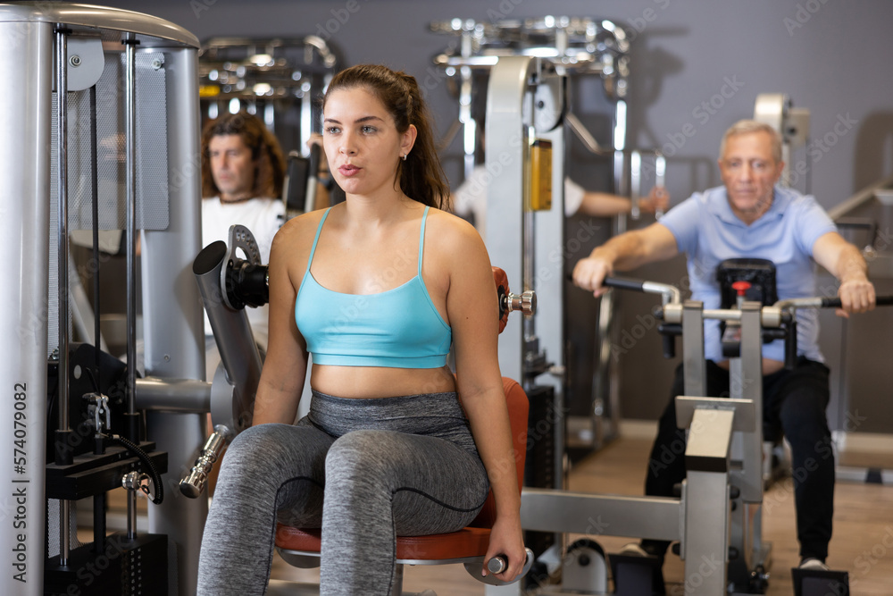 Sporty girl in activewear working out body muscles in modern gym ...