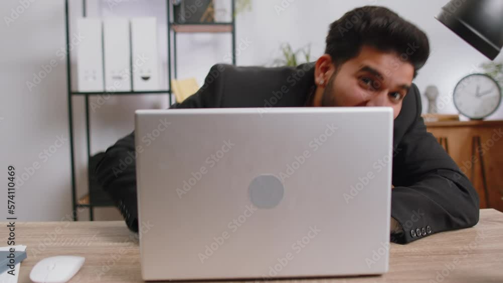 Indian businessman hiding behind laptop computer, making funny face ...