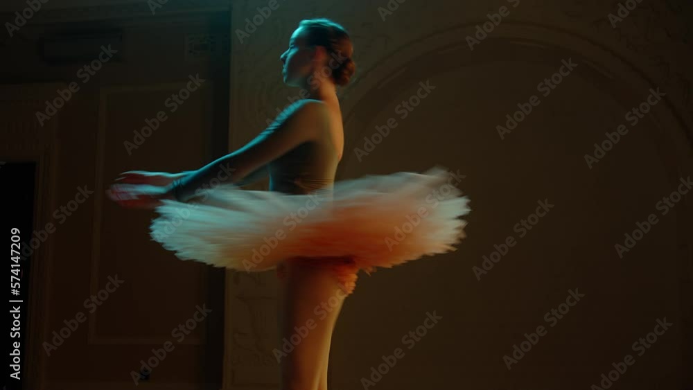 Cinematic shot of elegant ballerina in ballet dress performing on dim ...