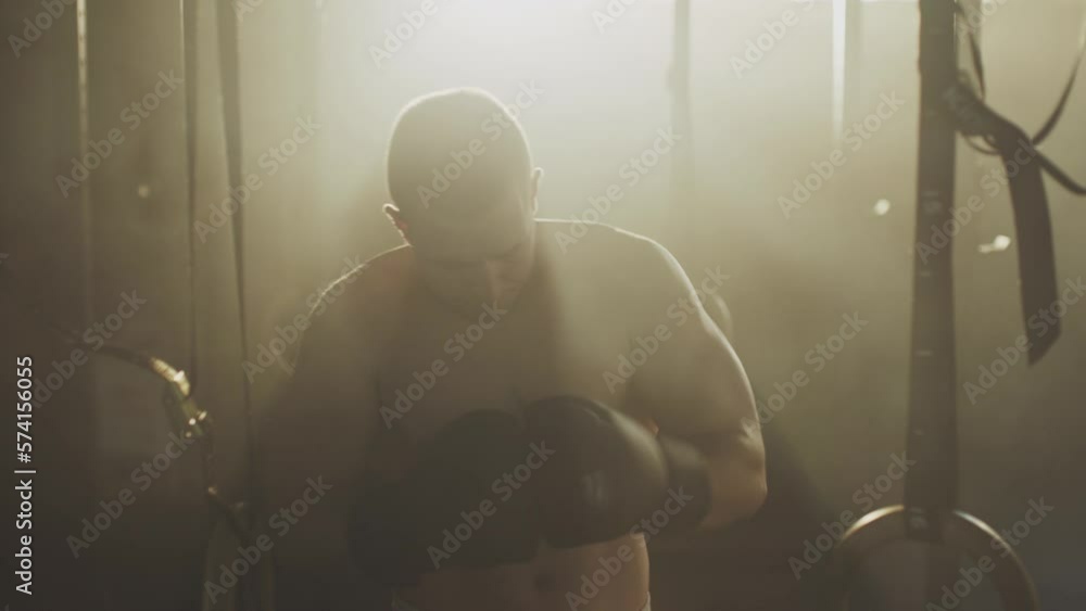 Shirtless male fighter wearing boxing gloves walking to the practice ground for practice in slow ...