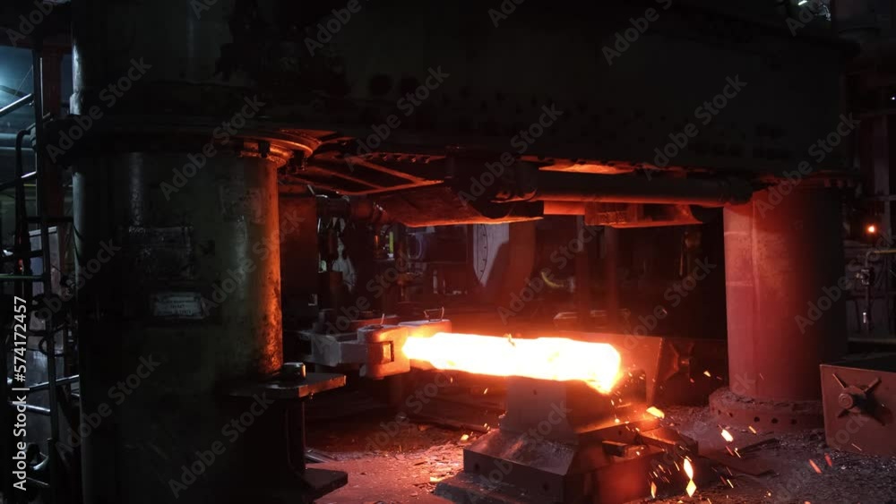 Blacksmith factory. Close-up of robots work. Forging a large hot metal billet with an industrial ...