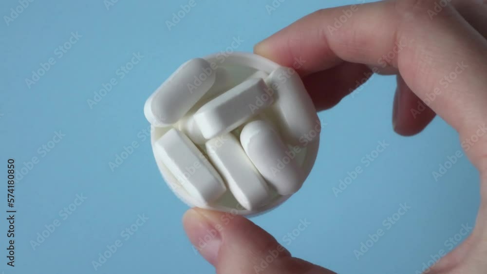 Magnesium Tablets. White tablets with rounded edges in a lid in a woman ...