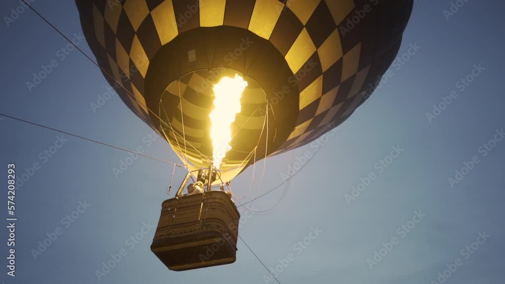 The hot air balloon rises with passengers. The strong flame is lit to ...