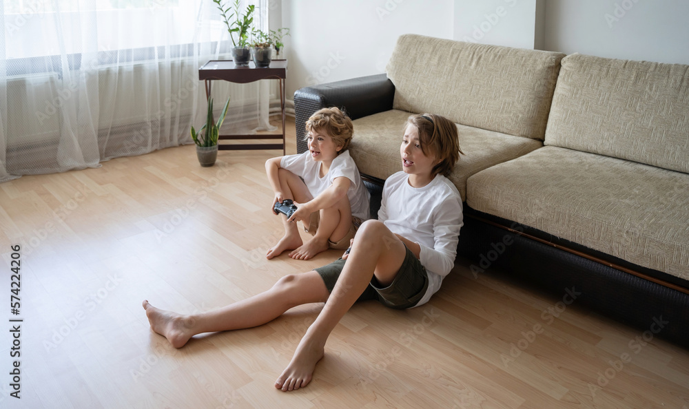 Funny caucasian siblings are relaxing together, playing video games in ...