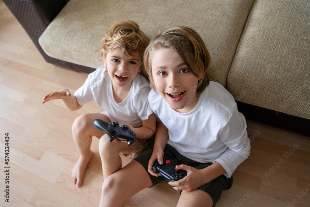 Funny caucasian brothers having fun together, playing video games with ...