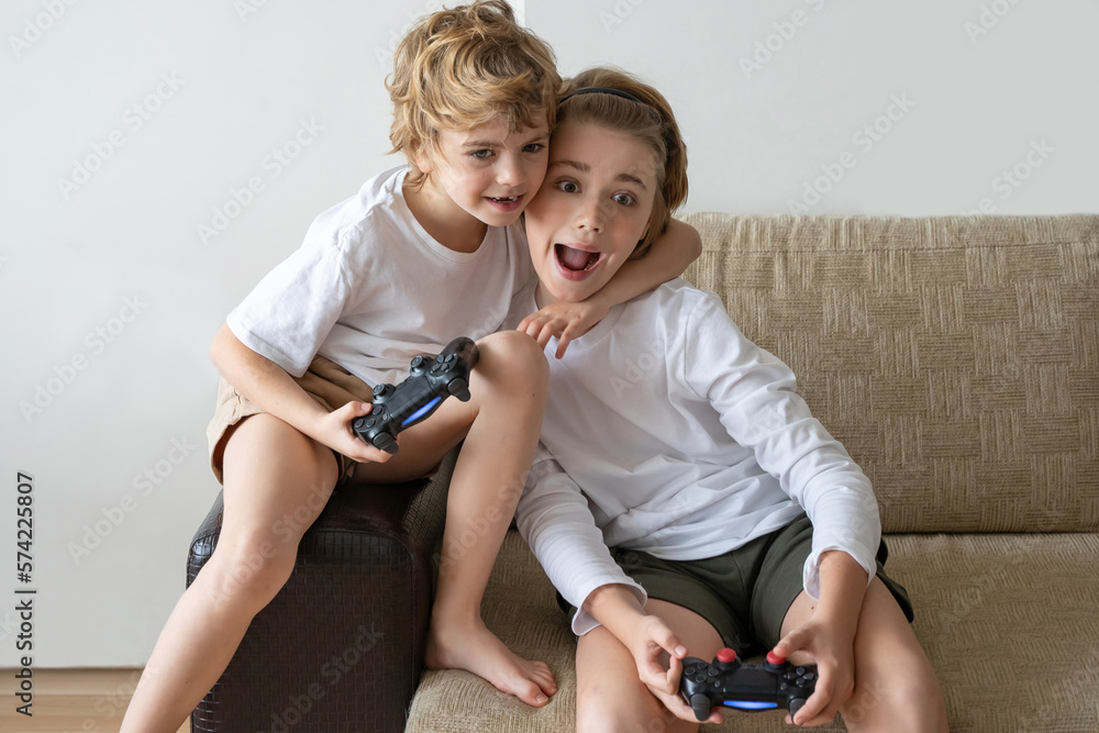 Excited children playing video games PS5 XBOX controller console two ...