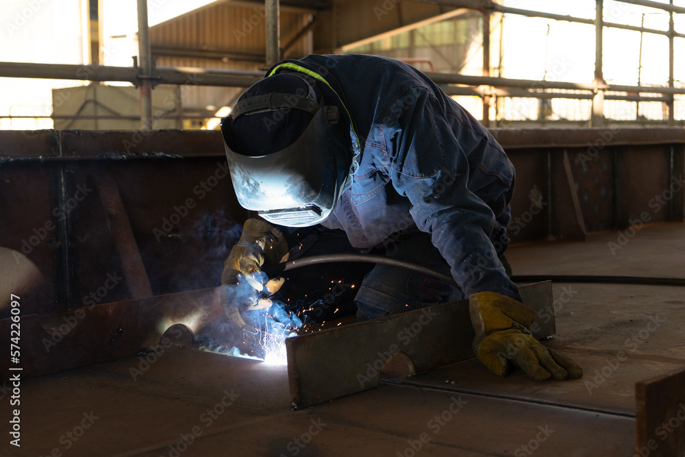 Photo & Art Print Welder welding a steel plate at a shipyard and a ...