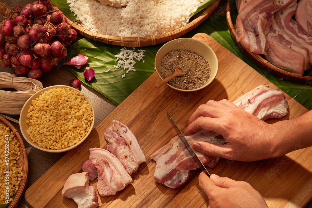 Model hand is slicing pork as ingredients for making sticky rice cake ...