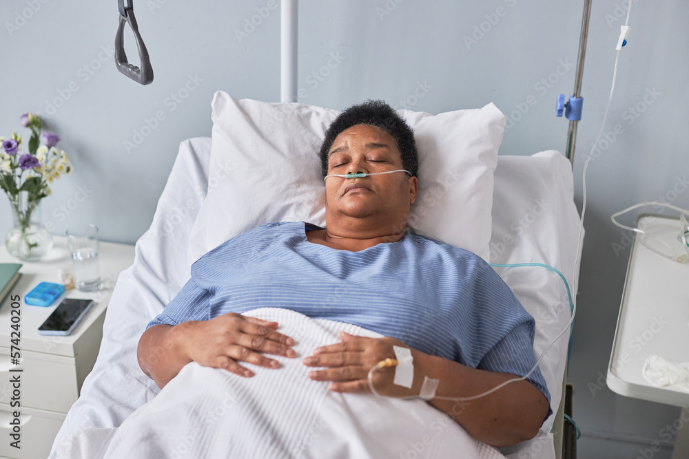 Black senior woman laying on bed in hospital room with IV support, high ...
