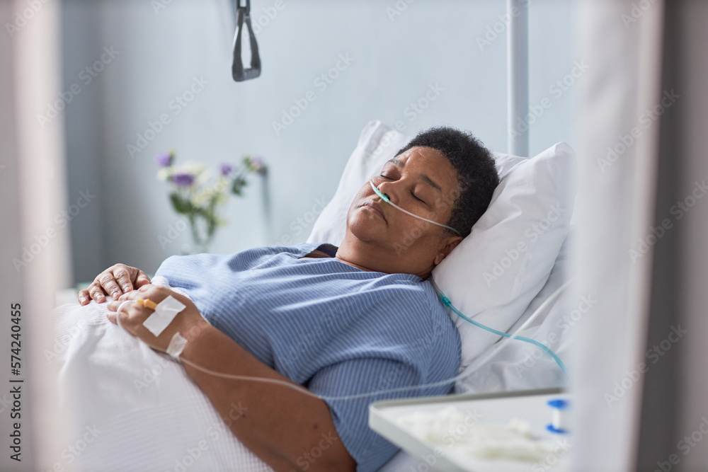 Senior female patient sleeping on bed in hospital room with oxygen ...
