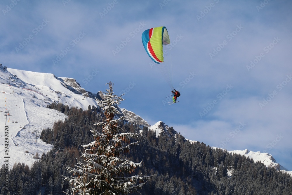 2 people paragliding in a tandem flight with a sunny winterlandscape ...
