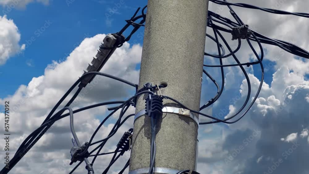 close up of concrete electricity pylon with messy wires on clear cloudy ...
