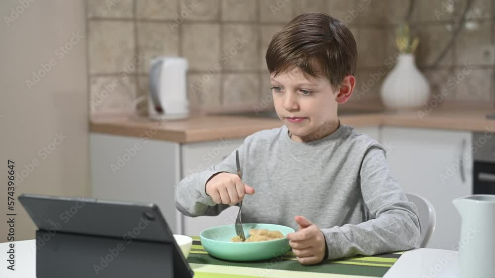 little boy is enjoying his time eating and watching cartoons on a ...