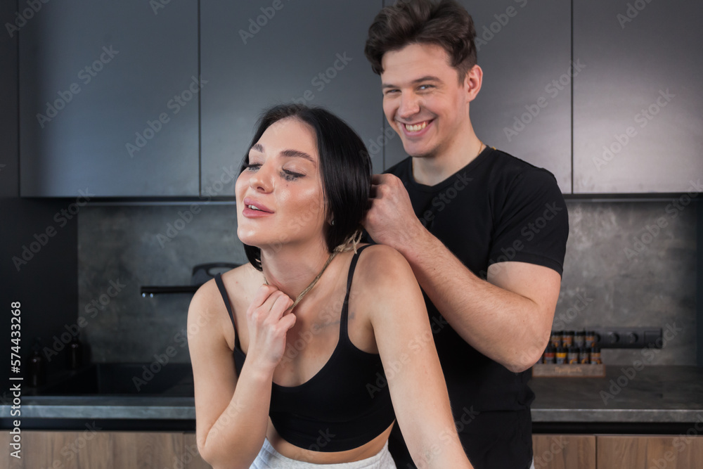 Domestic violence concept. A man strangles a woman with rope at home. A frightened young woman ...