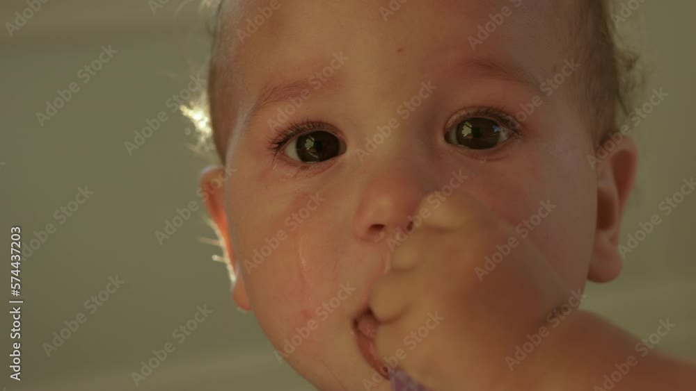 toddler girl with tears on her cheeks looks towards camera - close up ...