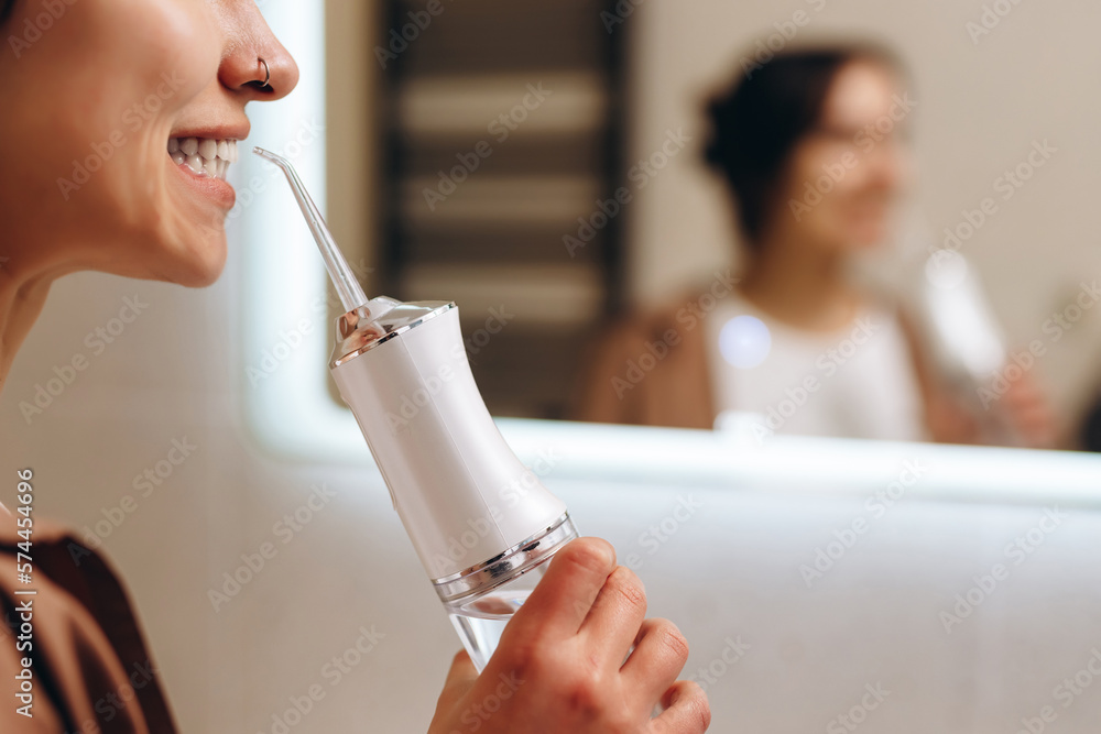 Cut view of happy young model holding oral water irrigator. One finger ...