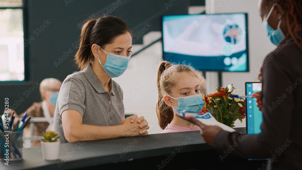 Two patients with face mask talking to facility receptionist at ...
